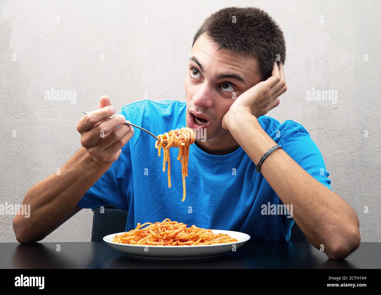 an young man eating spaghetti with inappetence Stock Photo - Alamy
