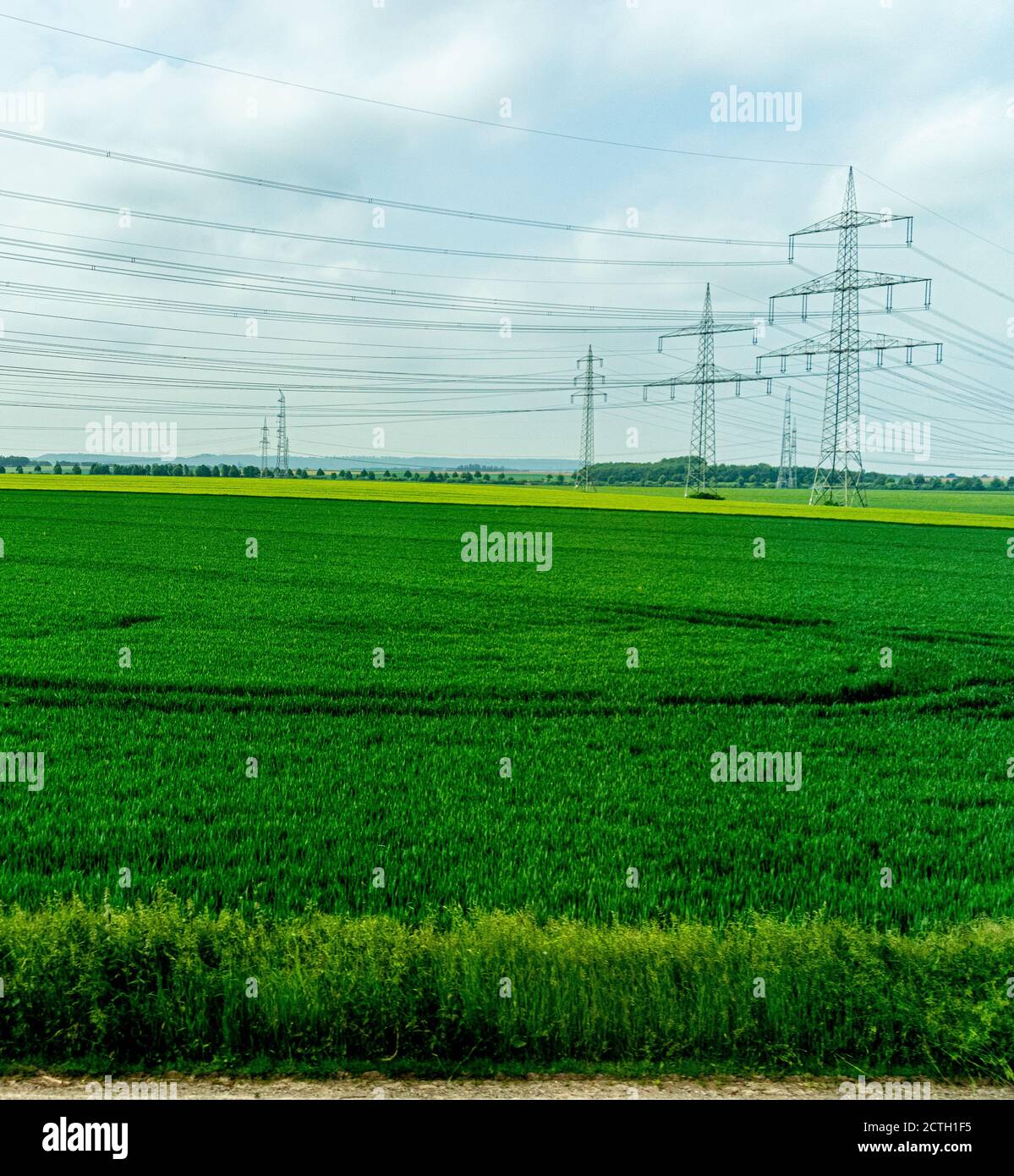 Overhead power lines in a green field Stock Photo - Alamy