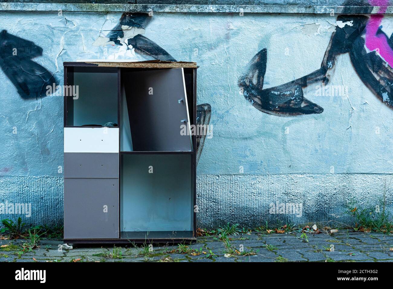 An old broken cupboard stands in front of a silver-sprayed wall, bulky ...