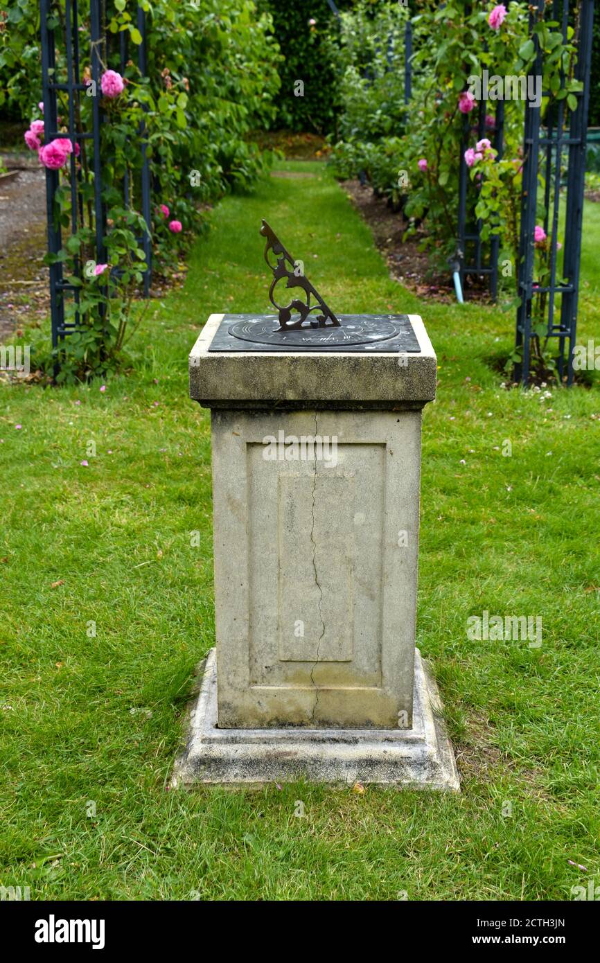 close up of sun dial mounted on a stone pillar set in a country garden ...