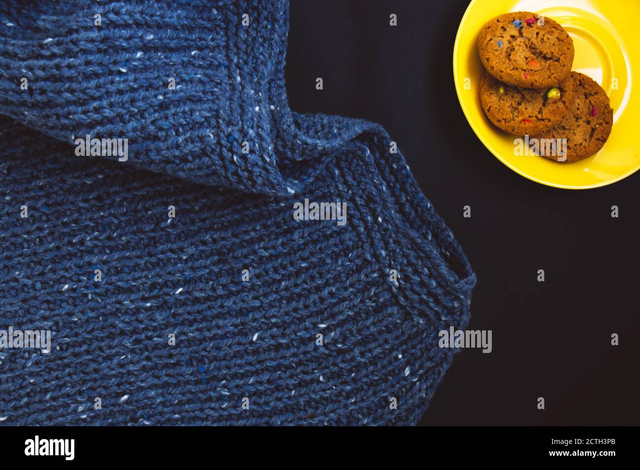 Blue knit sweater and yellow plate with flavored cookies with colored ...