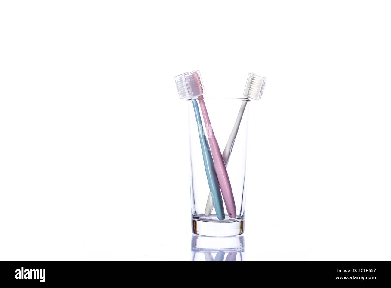 pastel shades toothbrushes with caps in glass isolated on white ...