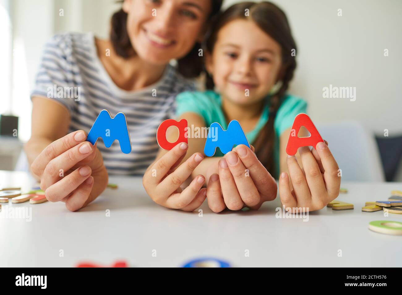 Happy mother and preschool daughter playing with set of wooden letters ...