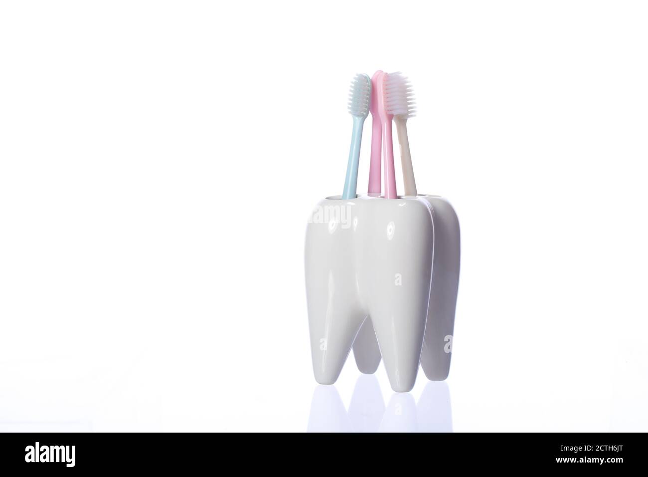 Four colorful toothbrushes in tooth-shaped container. White decorative ...
