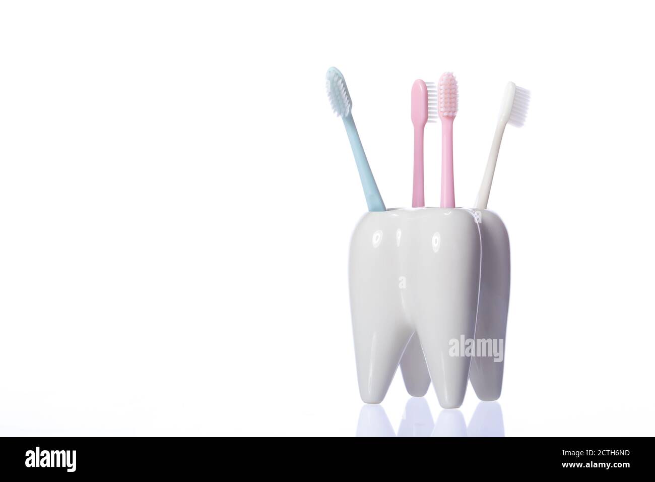 Four toothbrushes in ceramic tooth-shaped stand isolated on white ...