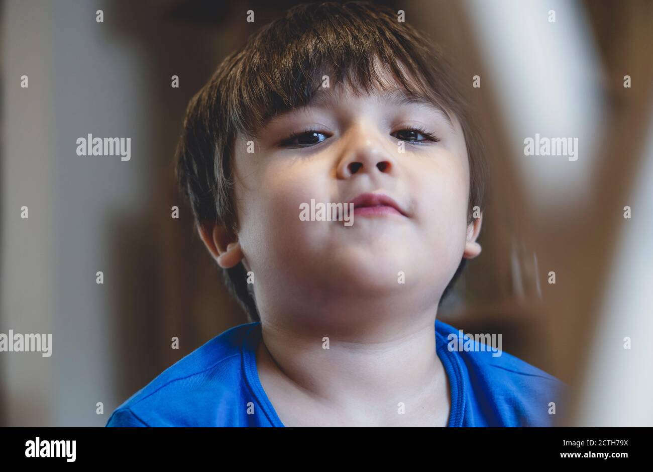 Close up little boy making funny face while looking at camera with ...