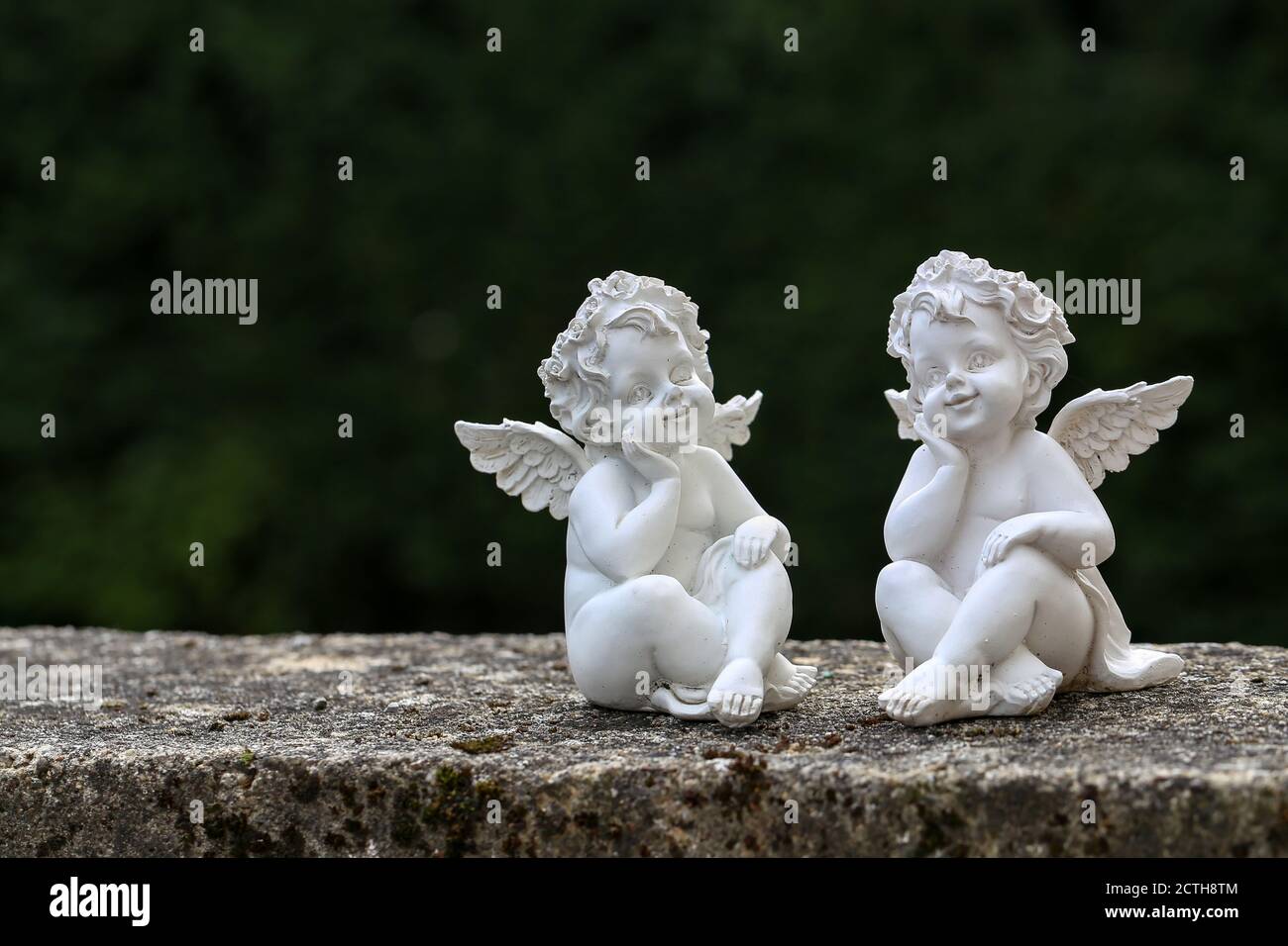 Two miniature angels on a stone wall Stock Photo - Alamy