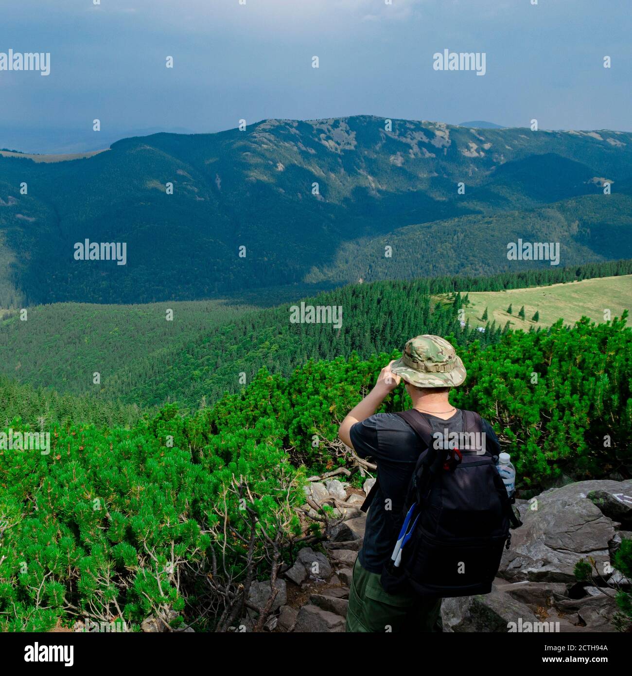 A tourist with a black backpack looks into the distance high in the ...