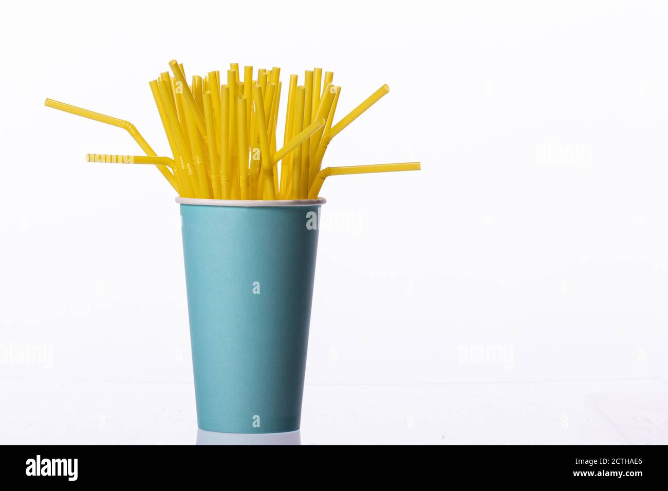 Yellow plastic flexible straws in blue paper cup isolated on white ...