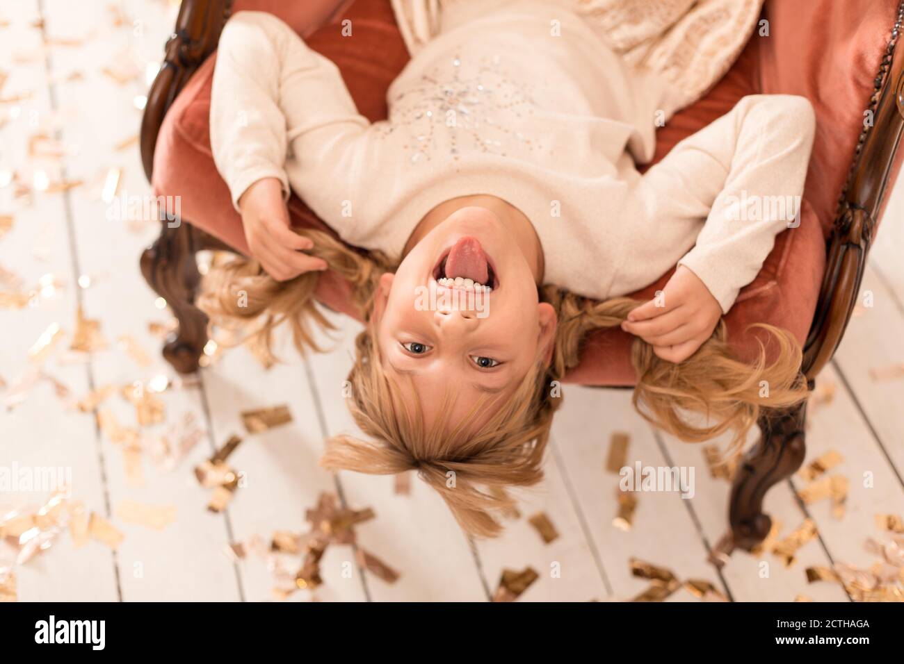 A little girl sits upside down in a chair. A hyperactive child Stock ...