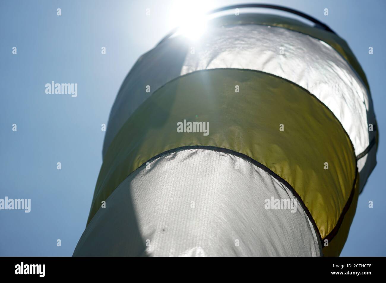 White - yellow wind sock on the pole on the blue sky background shot ...