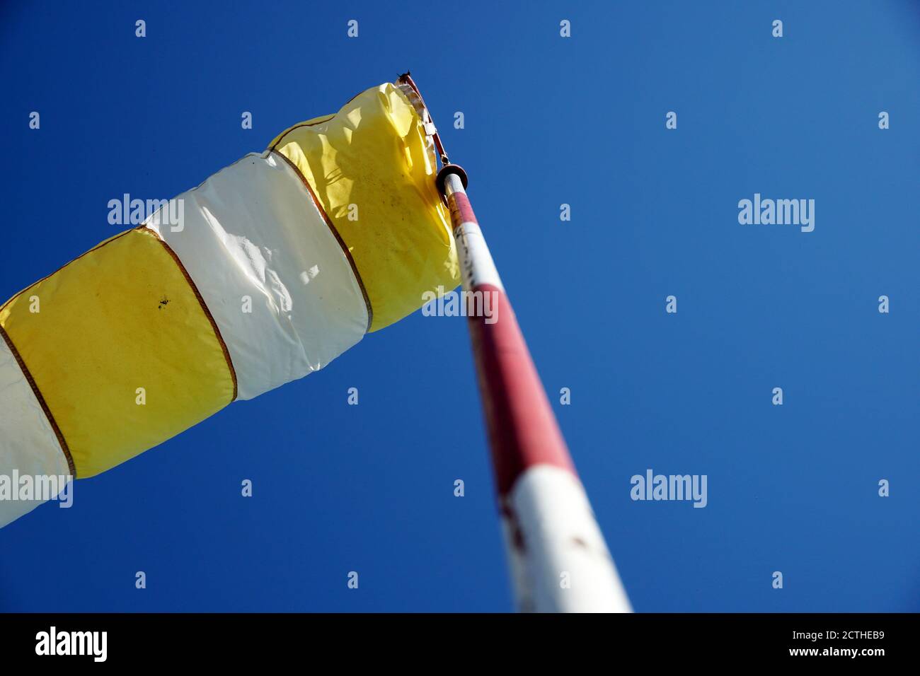 White - yellow wind sock on the pole on the blue sky background shot ...