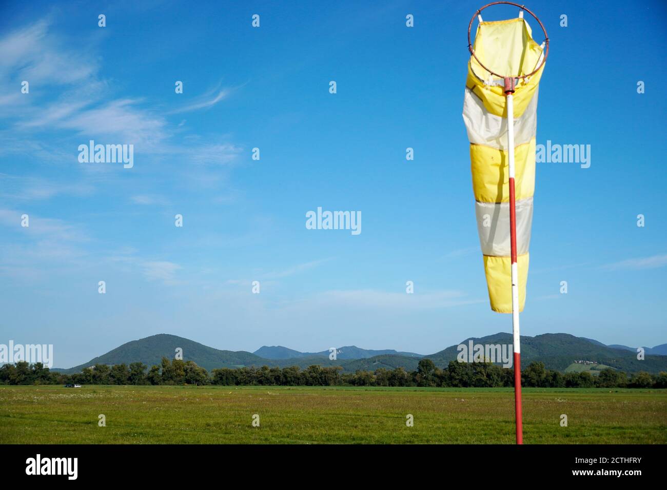 White - yellow wind sock on the pole on the blue sky background shot ...