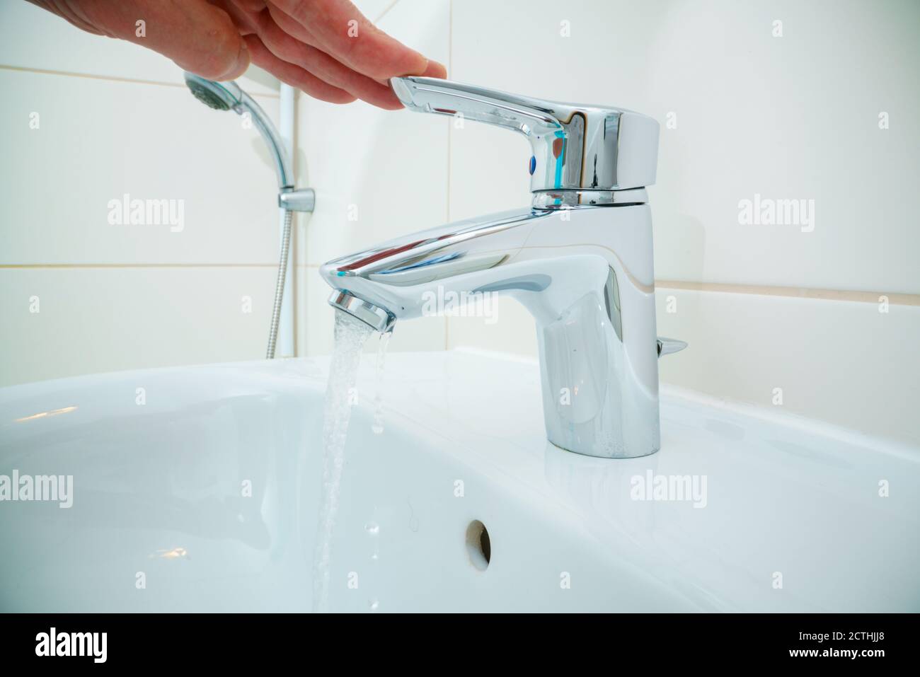 Man is closing water flow tap with water. Water running from chrome ...