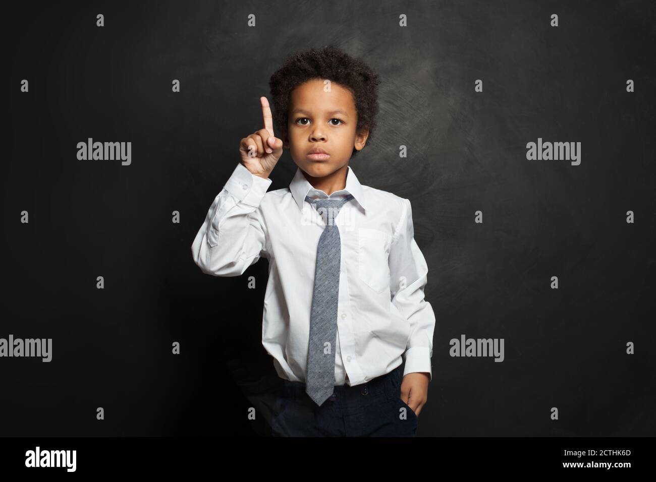 Serious black child student boy pointing up on black, portrait Stock ...
