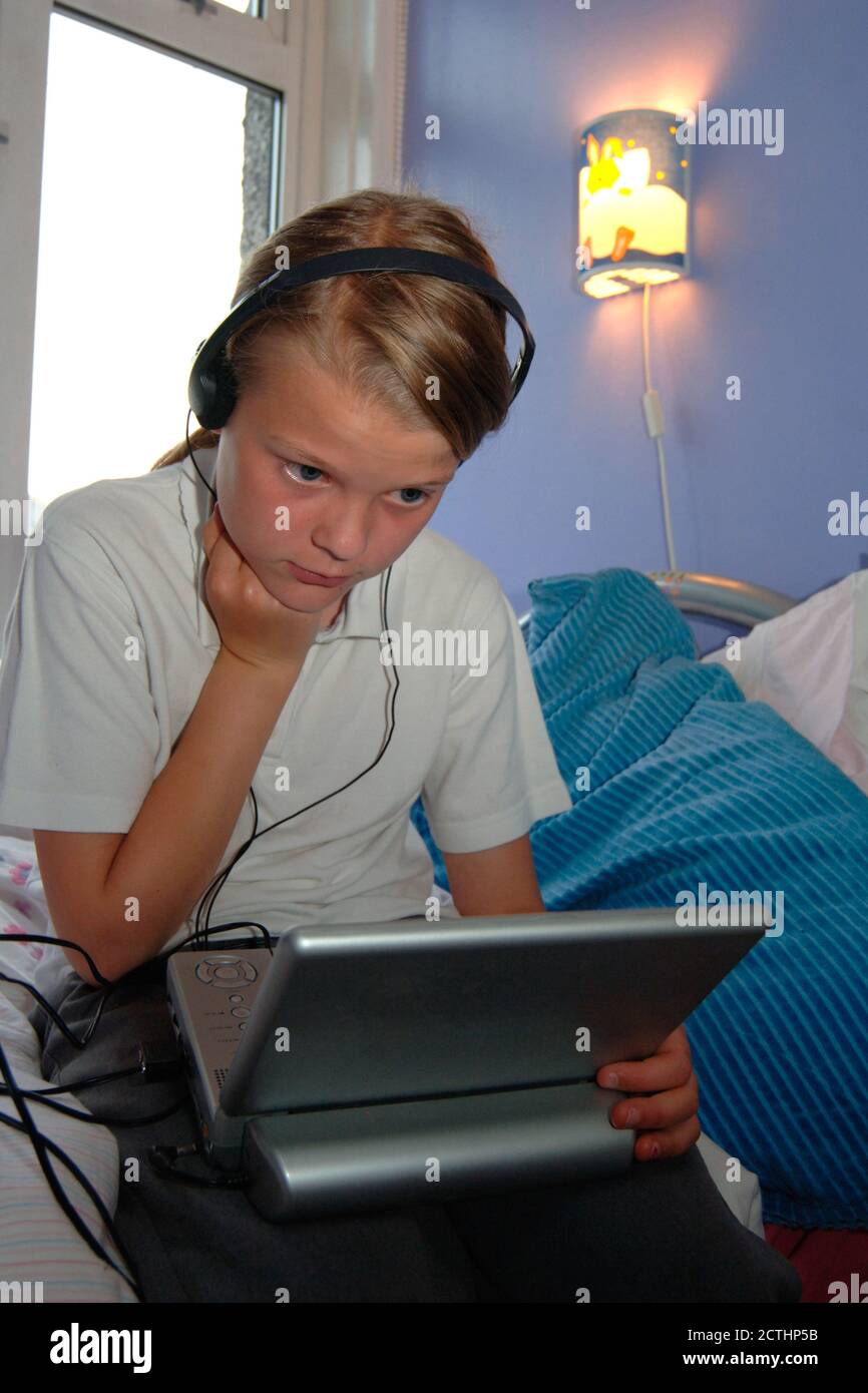 Girl watching DVD with headphones in her bedroom Stock Photo - Alamy