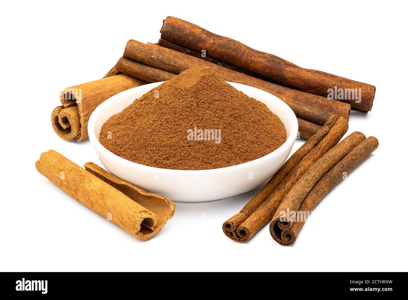 Ground cinnamon in white ceramic bowl and cinnamon sticks isolated on ...