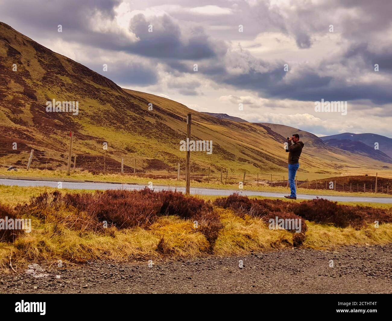 a male photographer takes a picture in the beautiful scottish highlands ...