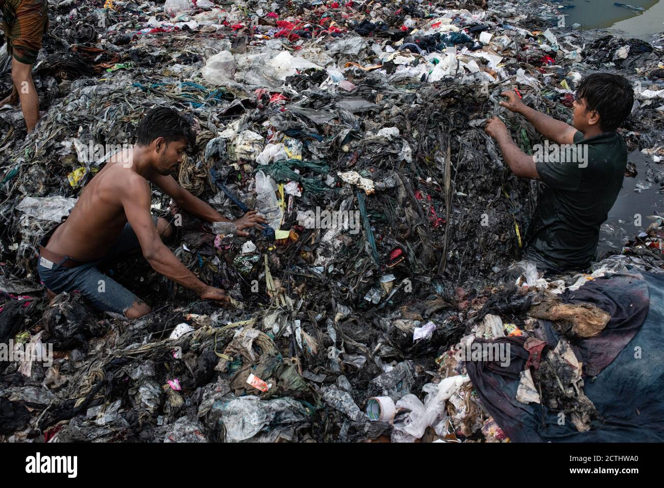 Bangladesh. 17th July, 2020. Volunteers swim neck-deep in the mountain of urban waste that has ...
