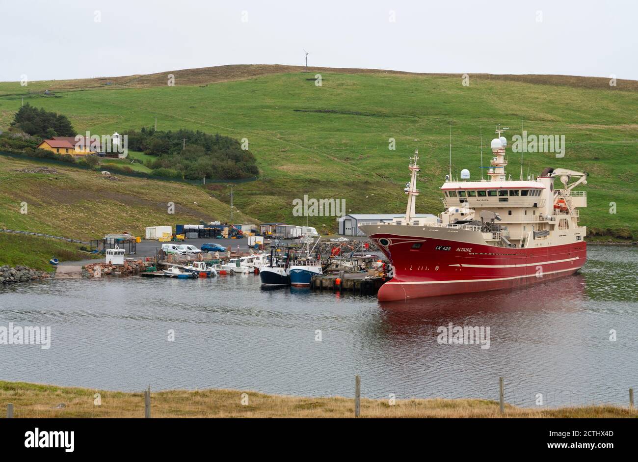 View of small harbour and pier with fishing vessels at Housetter, North ...