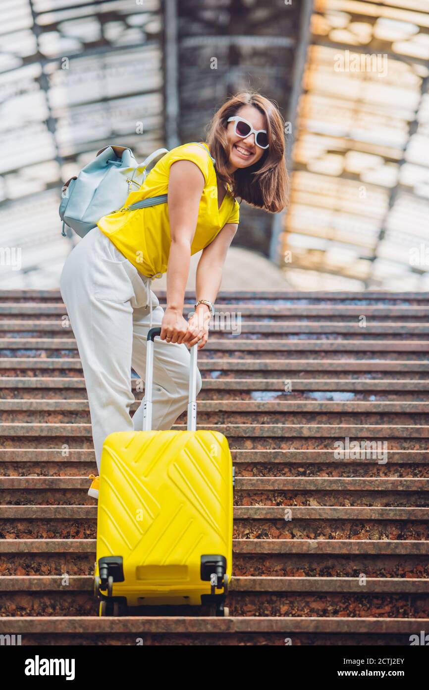 woman pulling up by stairs heavy yellow suitcase on wheels Stock Photo ...