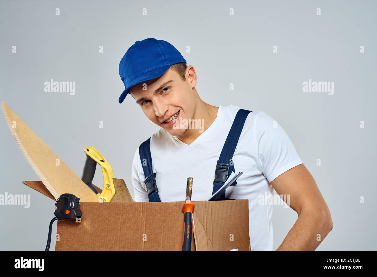 man in working uniform with a box in his hands tools loader delivery ...