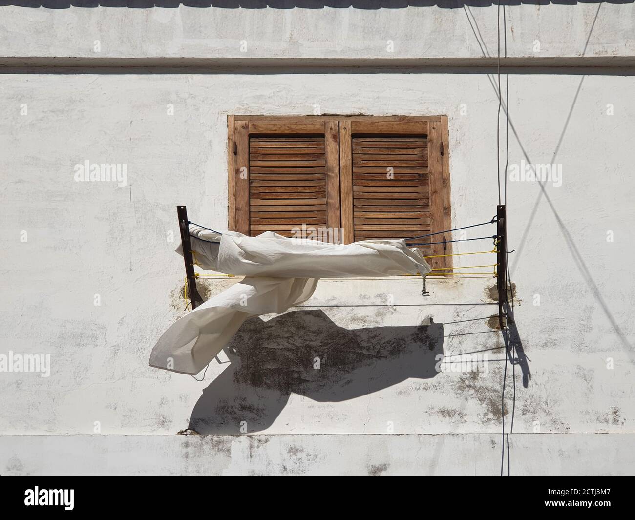 Old wooden brown window on a white wall, clothes are dried on a rope ...