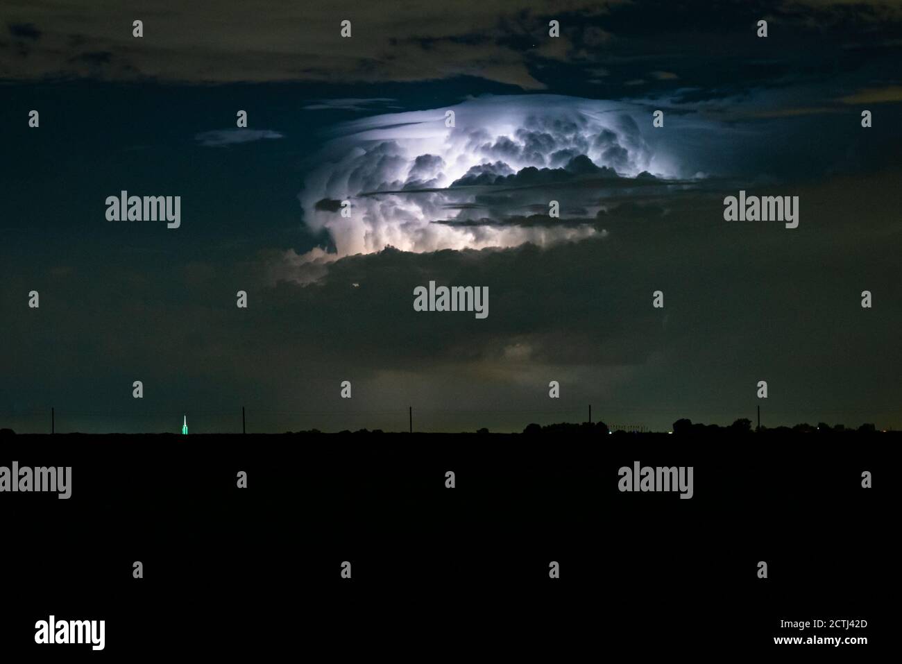 Distant supercell thunderstorm is lit by lightning at night Stock Photo ...