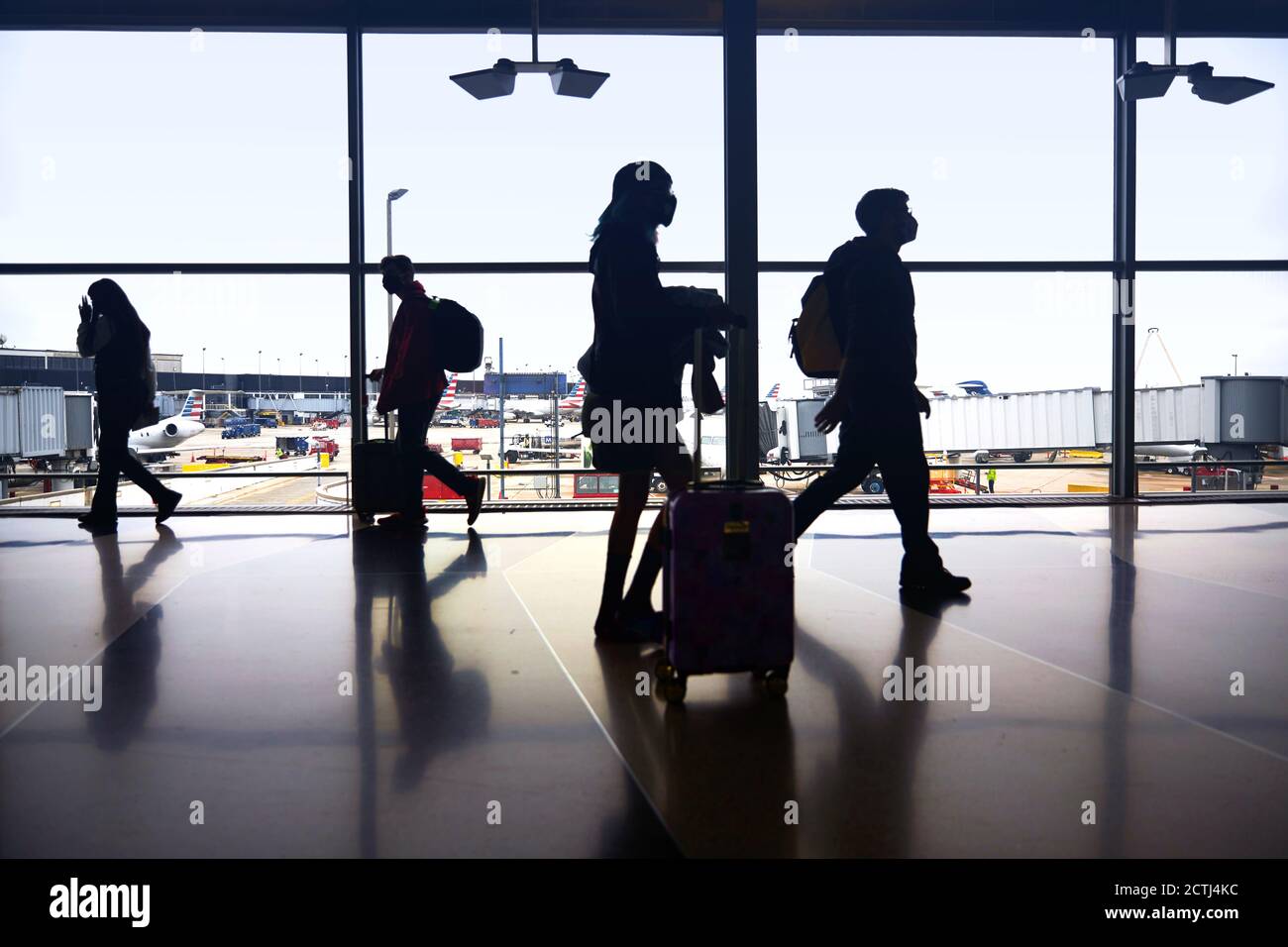 Silhouettes of airline travelers move between terminals to catch ...