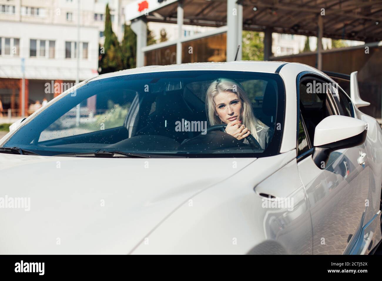 Beautiful female blonde driver behind the wheel of a car on the road ...