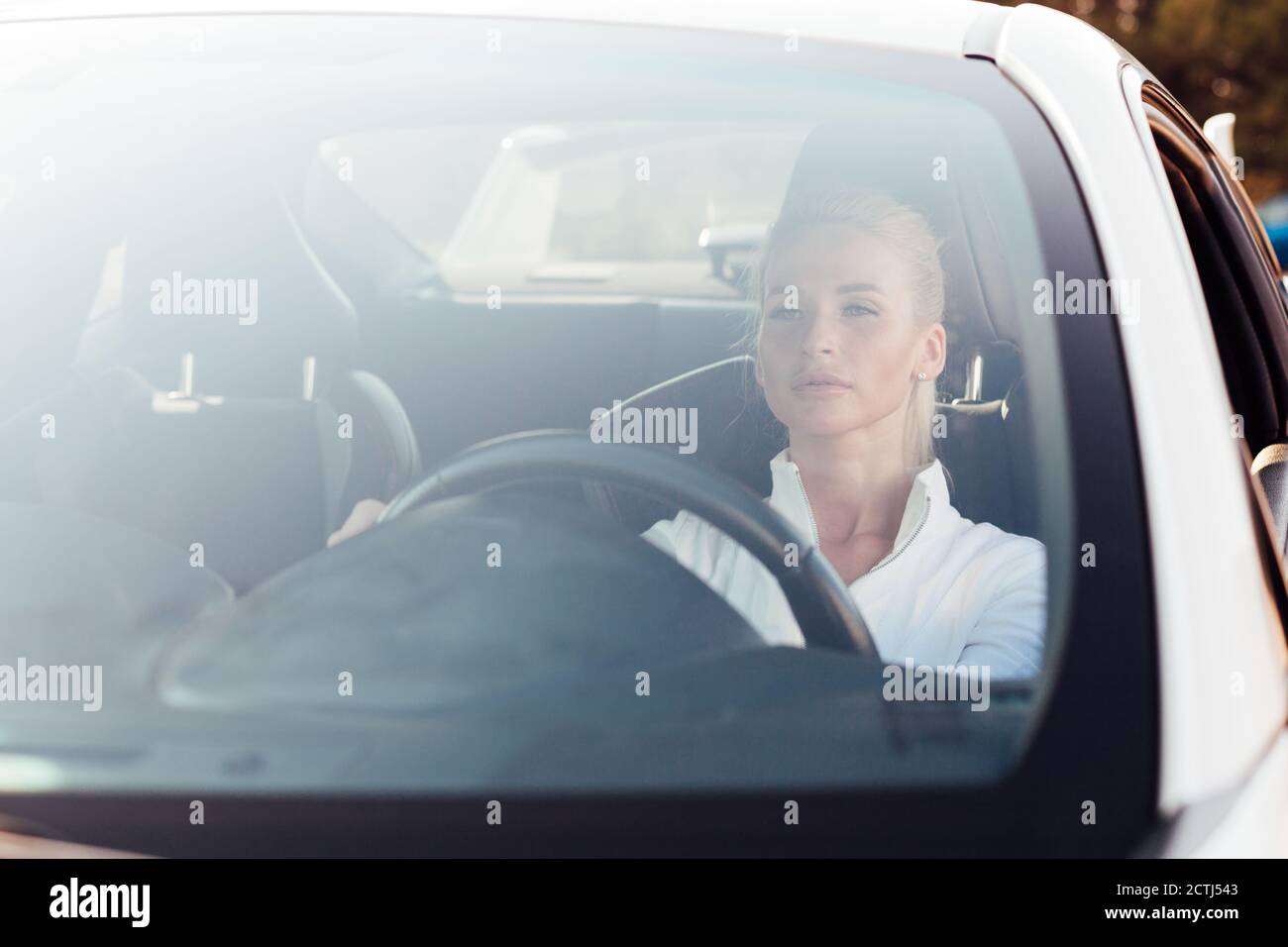 Beautiful female blonde driver behind the wheel of a car on the road ...