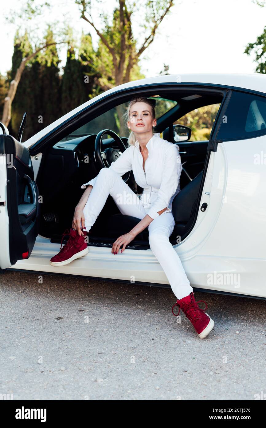 Beautiful female blonde driver behind the wheel of a car on the road ...