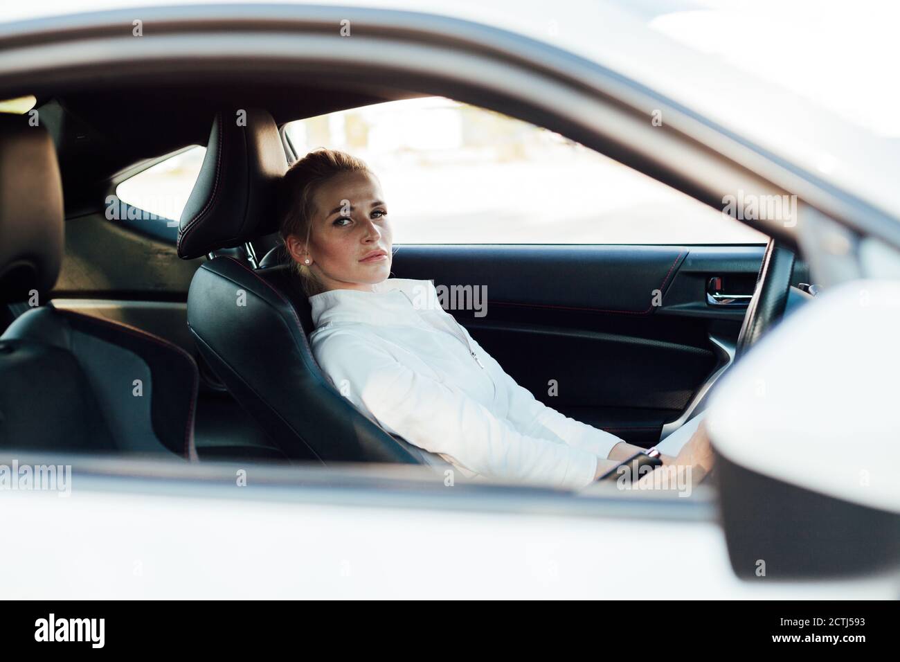 Beautiful female blonde driver behind the wheel of a car on the road ...
