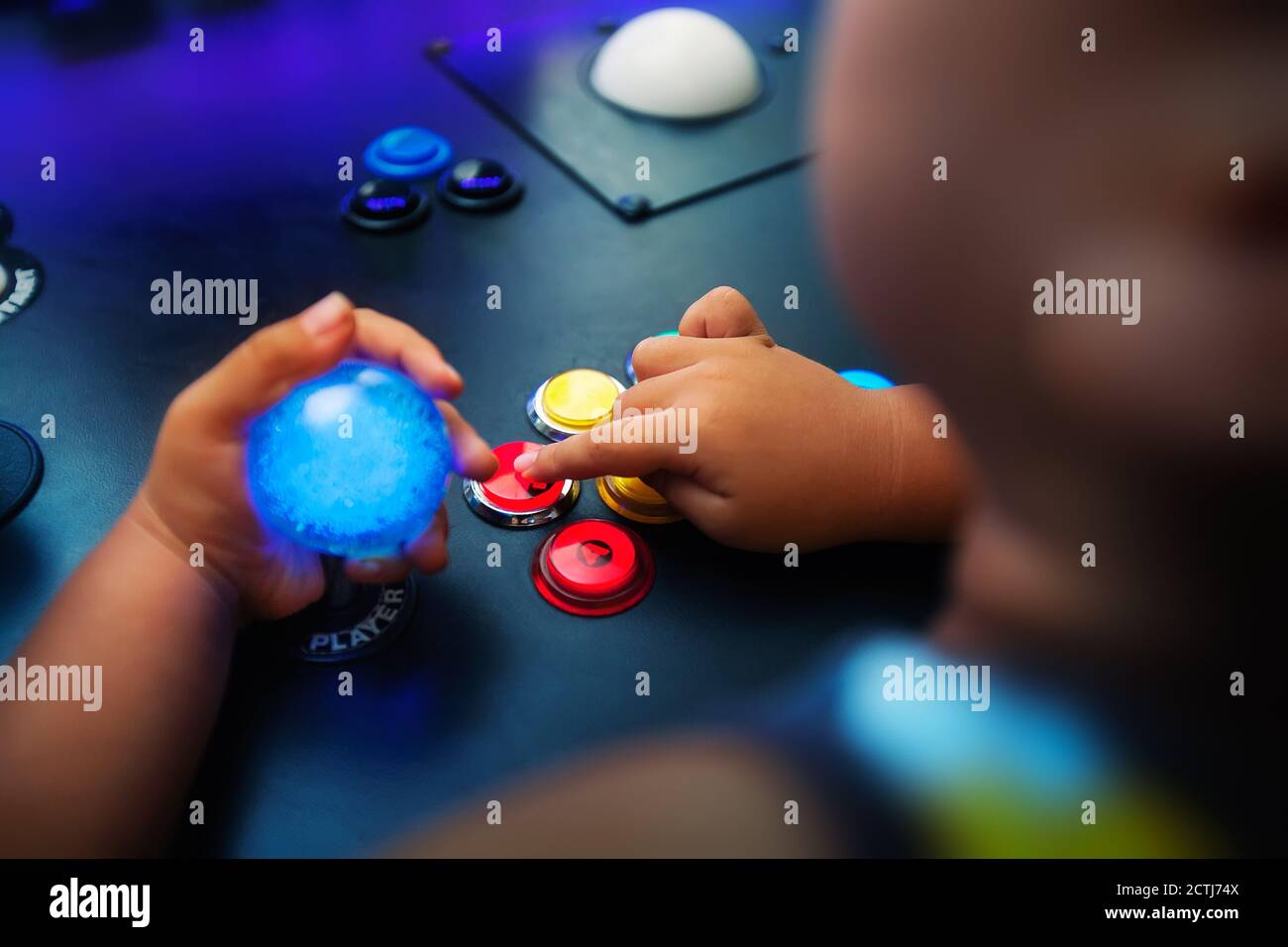 A young boy playing video games on a home arcade with push buttons ...