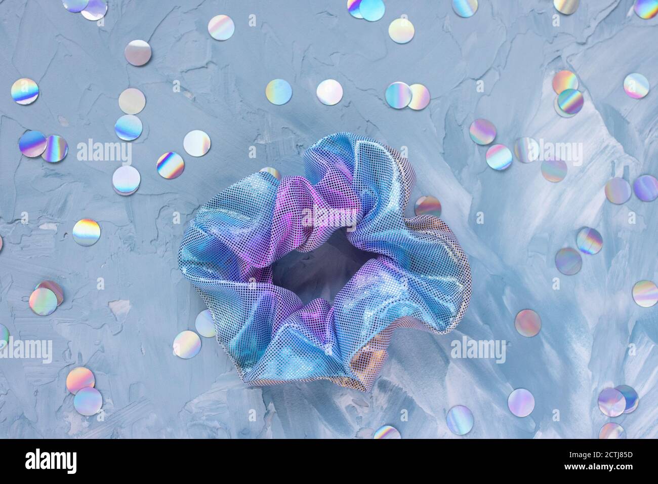 Trendy holographic scrunchie and confetti on blue Stock Photo - Alamy