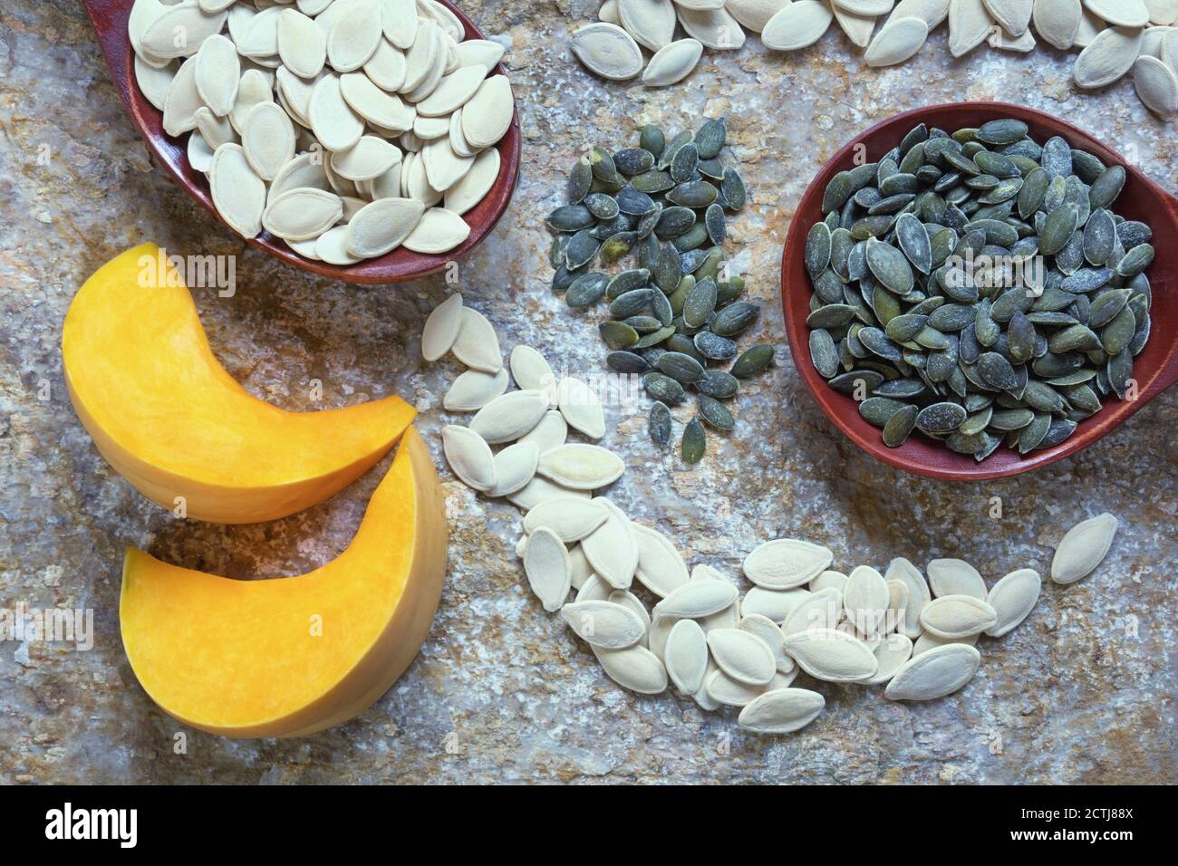 Pumpkin slices and seeds - in shell and peeled. Two large wooden spoons ...