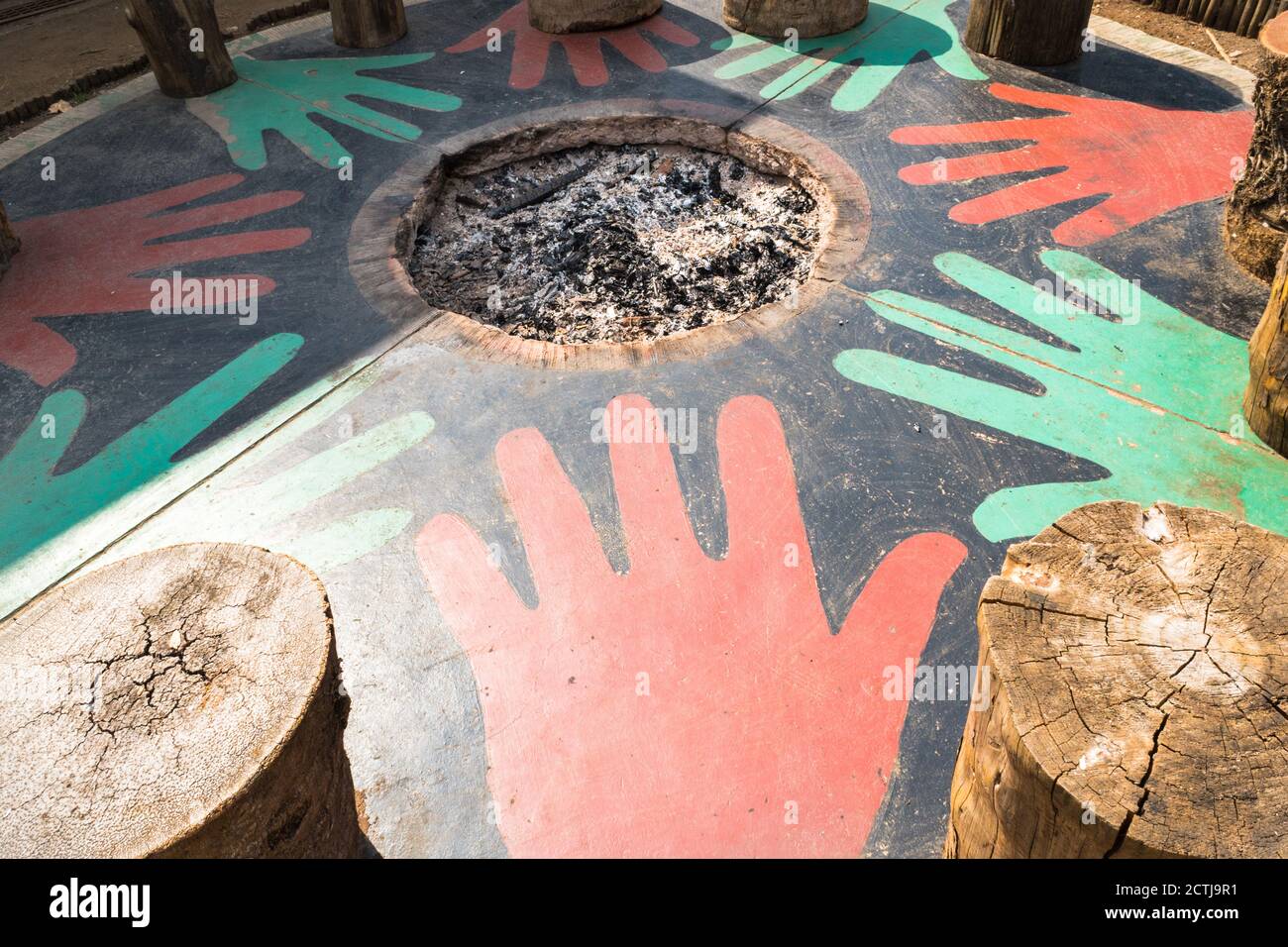 fire pit with colourful hands decorated around the perimeter outdoors ...