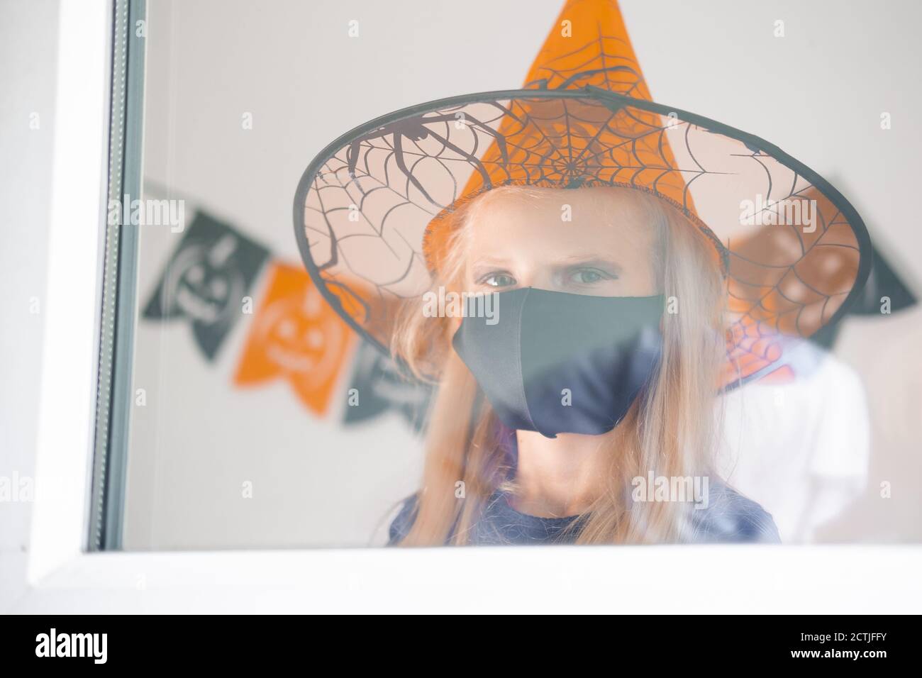 Portrait sad blonde girl in witch costume wearing face masks looking ...