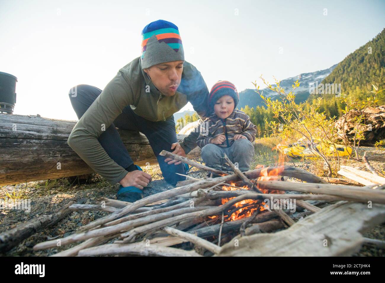 Father and son work together to start a fire at wilderness campsite ...