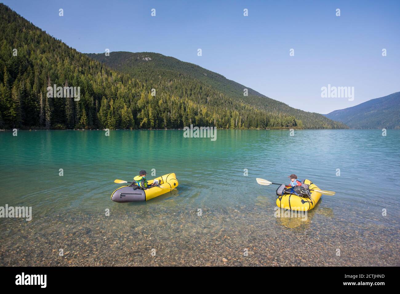 Two young boys learning how to paddle kayak on scenic lake Stock Photo ...