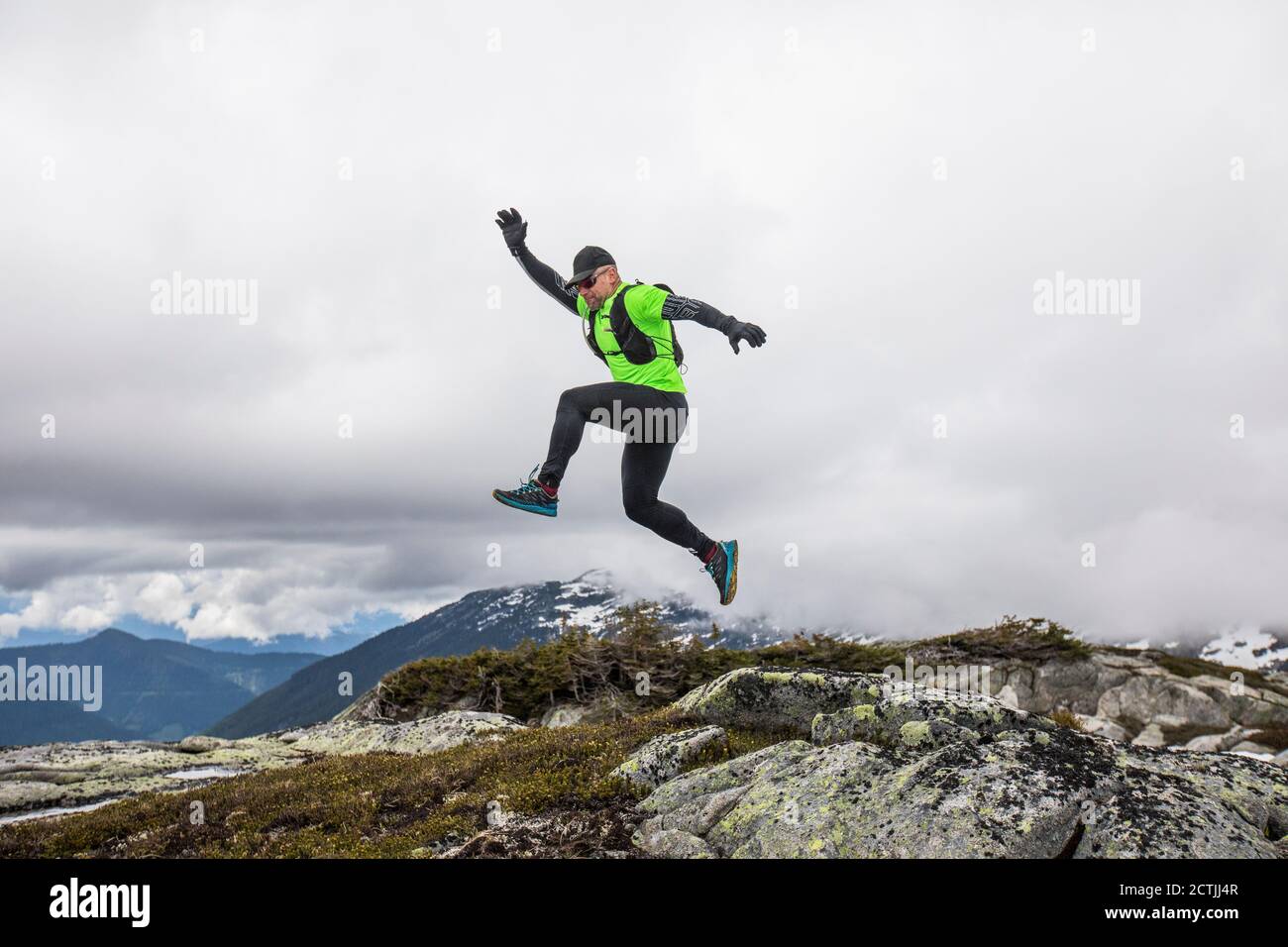 Trail runner jumps off rocks on mountain ridge Stock Photo - Alamy