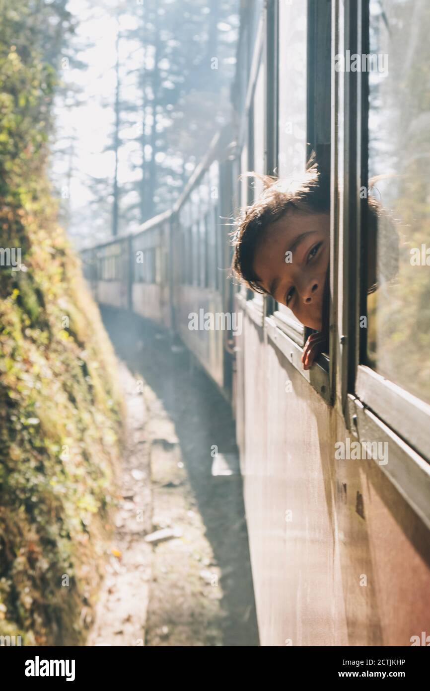 Young boy smiling through Toy Train window, while train goes up from ...