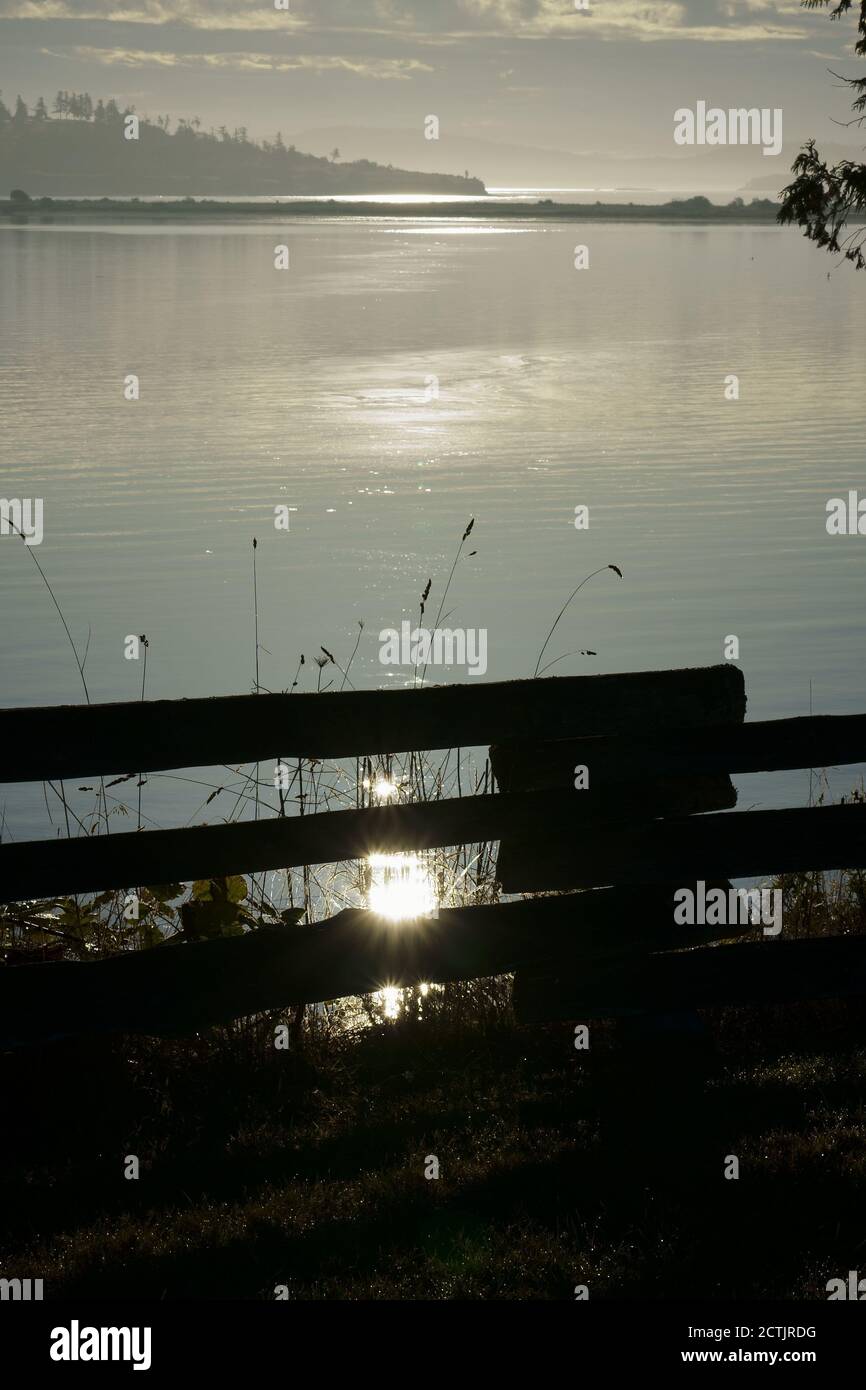 Sun reflecting off the bay through a split rail fence Stock Photo - Alamy