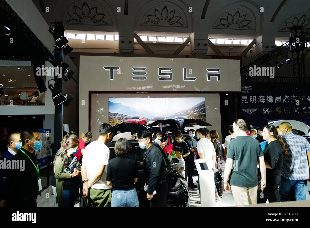 Visitors flock to the booth of Tesla, an American electric vehicle and ...