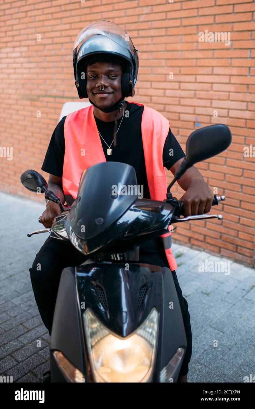 Happy delivery man on motorbike Stock Photo - Alamy