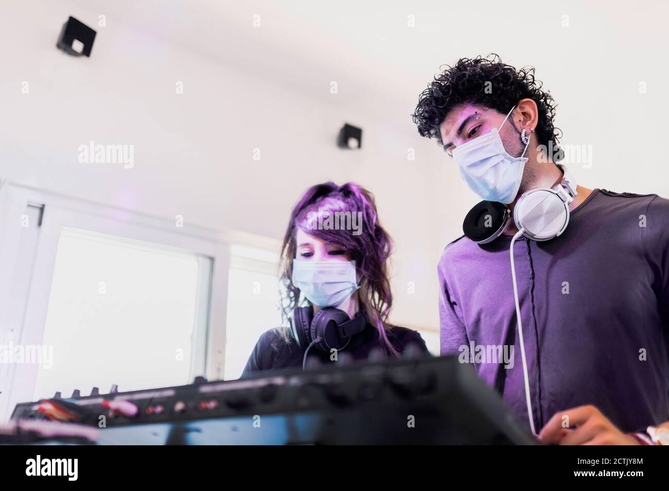 Couple wearing face masks while mixing techno sound at recording studio ...