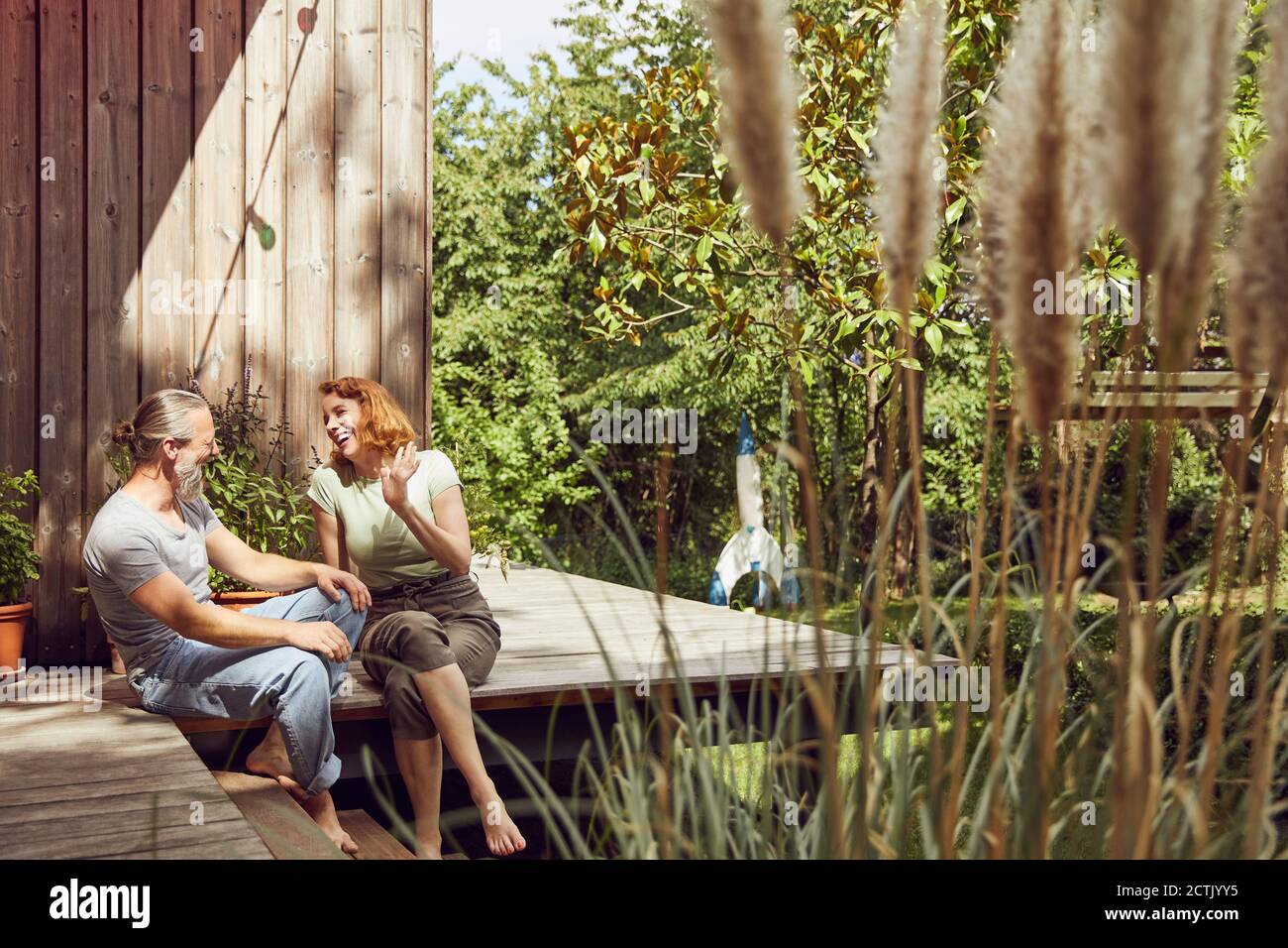 Cheerful couple talking while sitting outside tiny house in yard Stock ...
