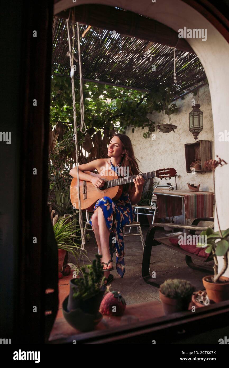 Young woman playing guitar in balcony seen through arch window Stock ...
