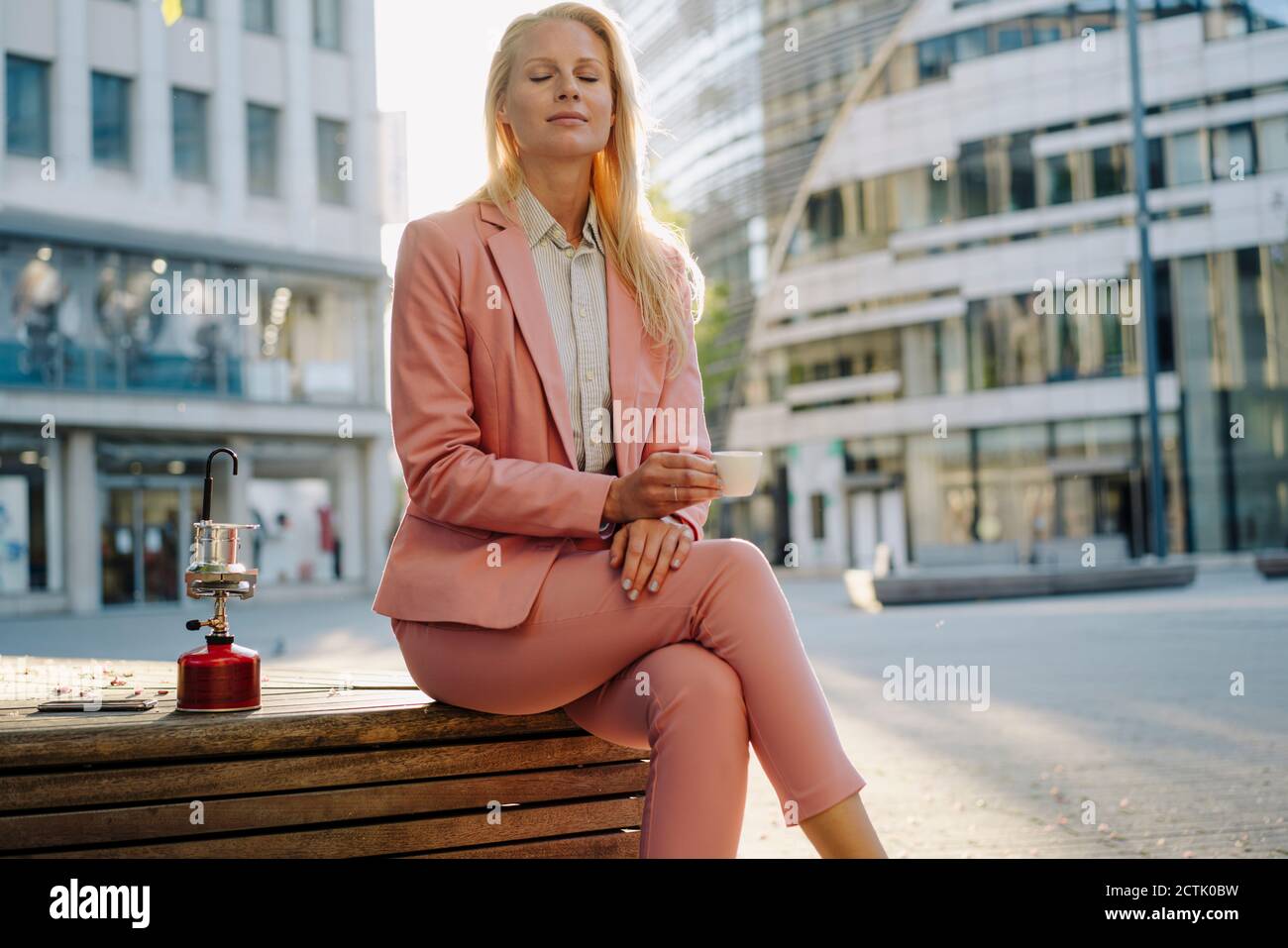 Relaxed female professional sitting with eyes closed by camping stove ...