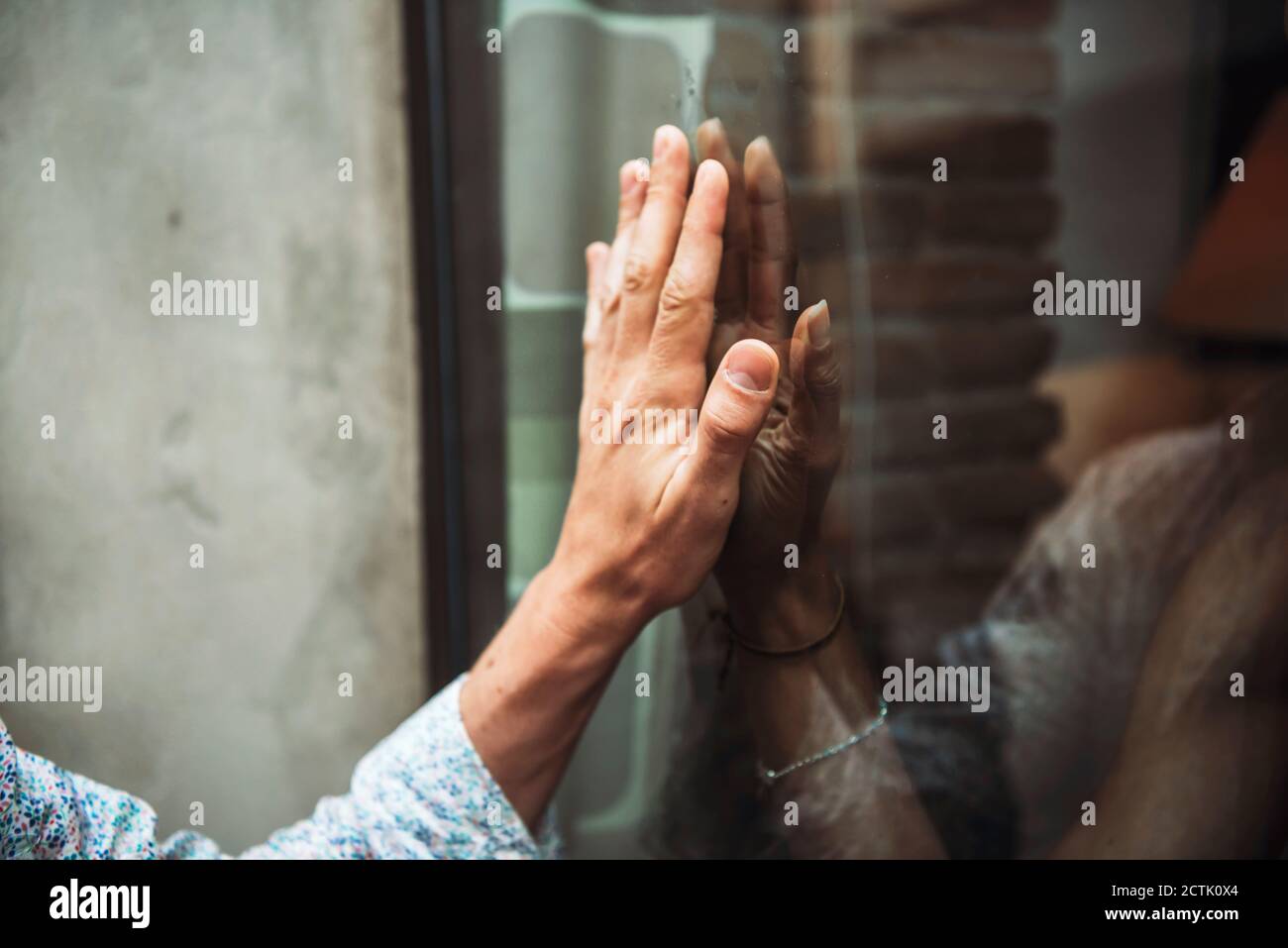 Close-up of couple hands touching each other through cafe's window ...